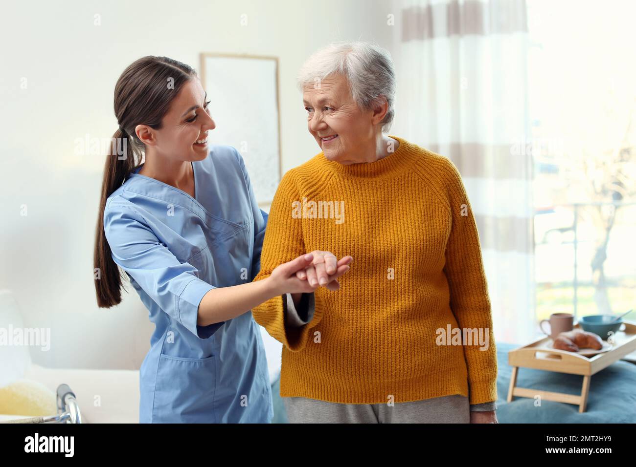 Care worker helping elderly woman to walk in geriatric hospice Stock ...