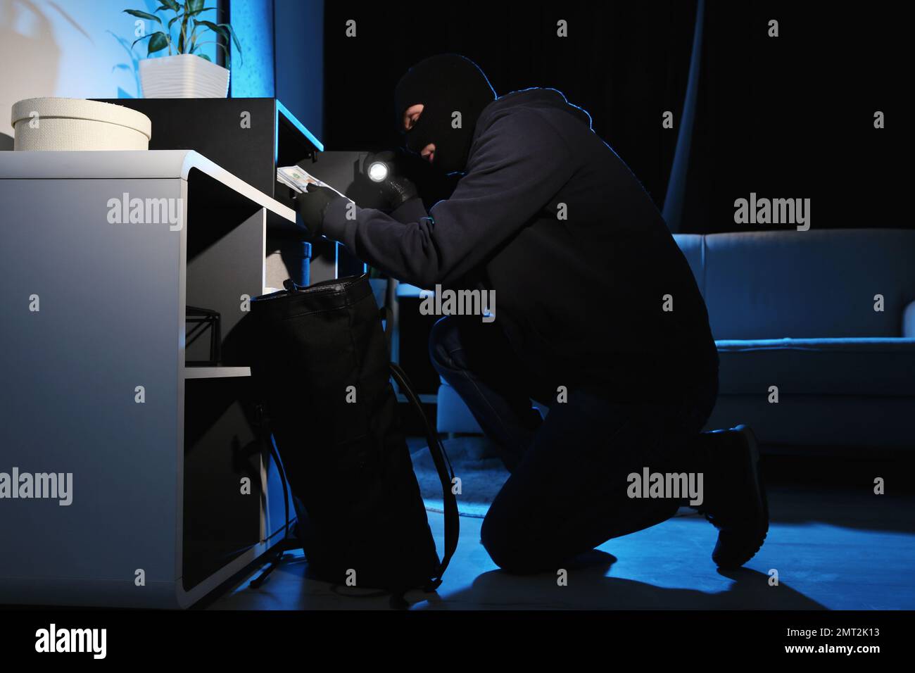 Thief taking money out of steel safe indoors at night Stock Photo - Alamy