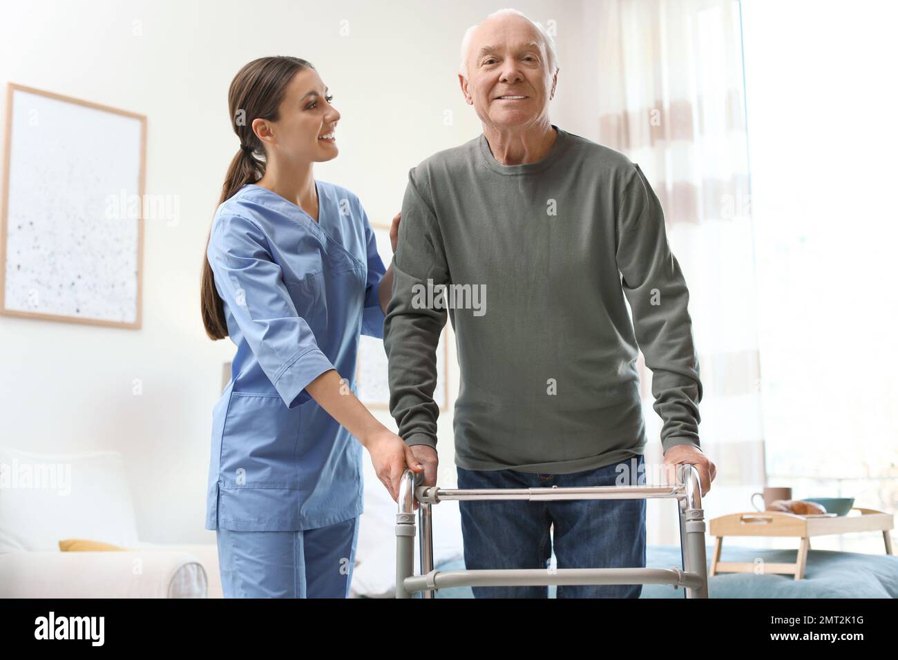 Care worker helping elderly man with walker in geriatric hospice Stock ...