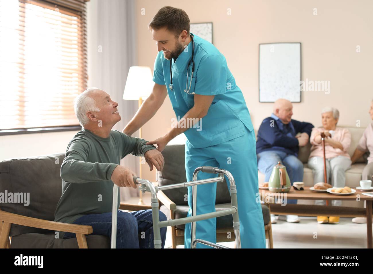 Medical worker taking care of elderly man with walker in geriatric ...