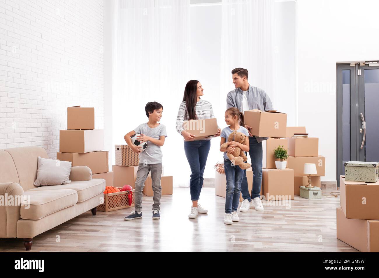 Happy family in room with cardboard boxes on moving day Stock Photo - Alamy