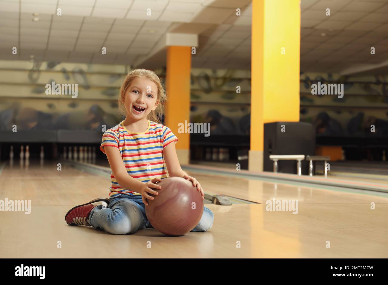 Little girl with ball in bowling club Stock Photo - Alamy