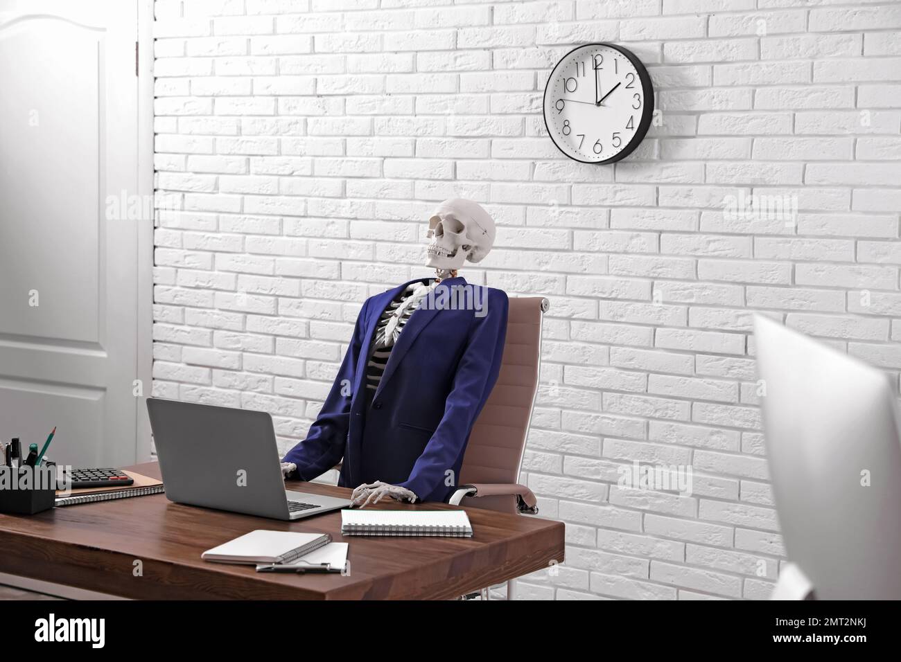 Human skeleton in suit using laptop at table in office Stock Photo - Alamy