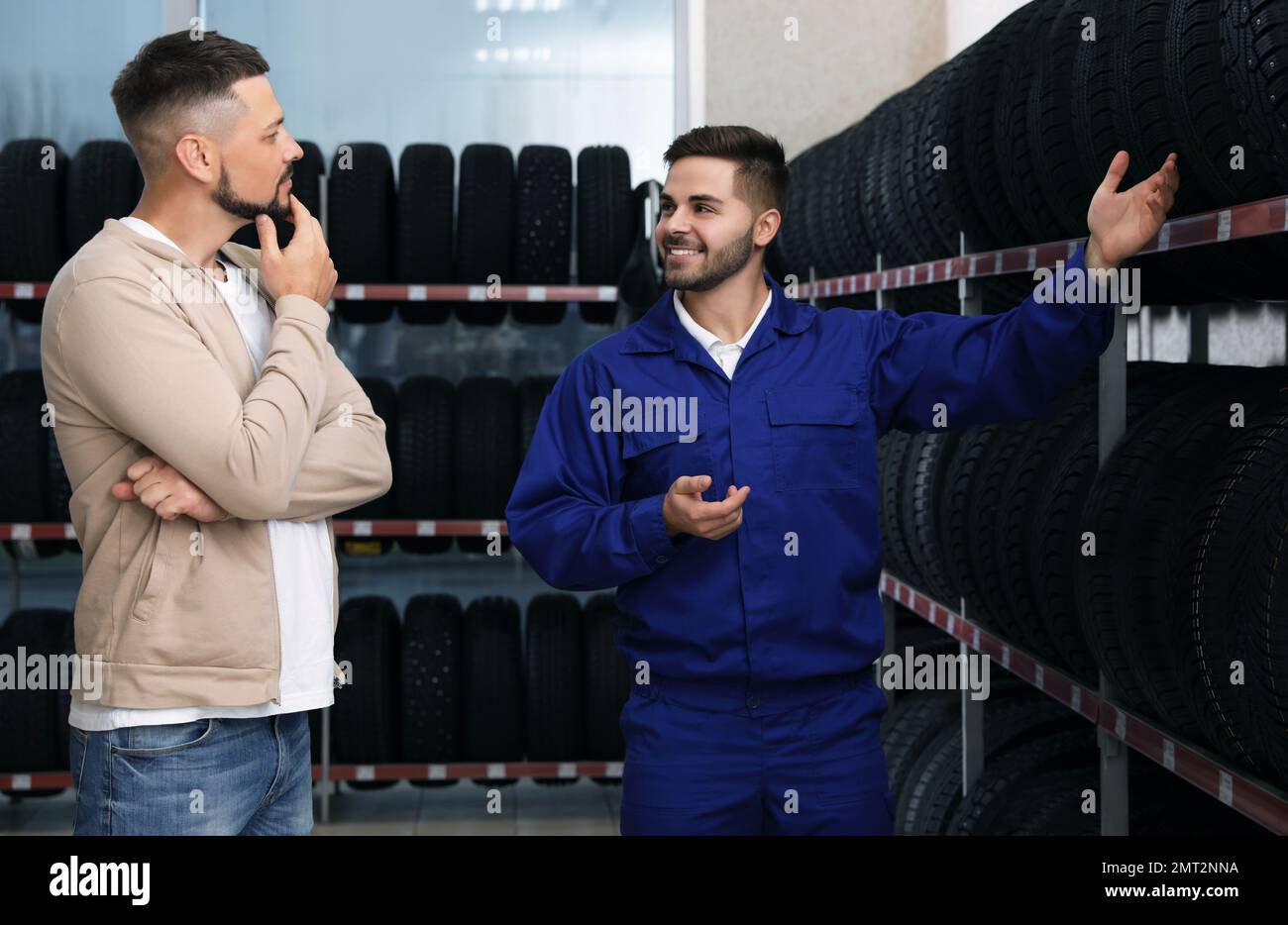 Mechanic helping client to choose car tire in auto store Stock Photo ...