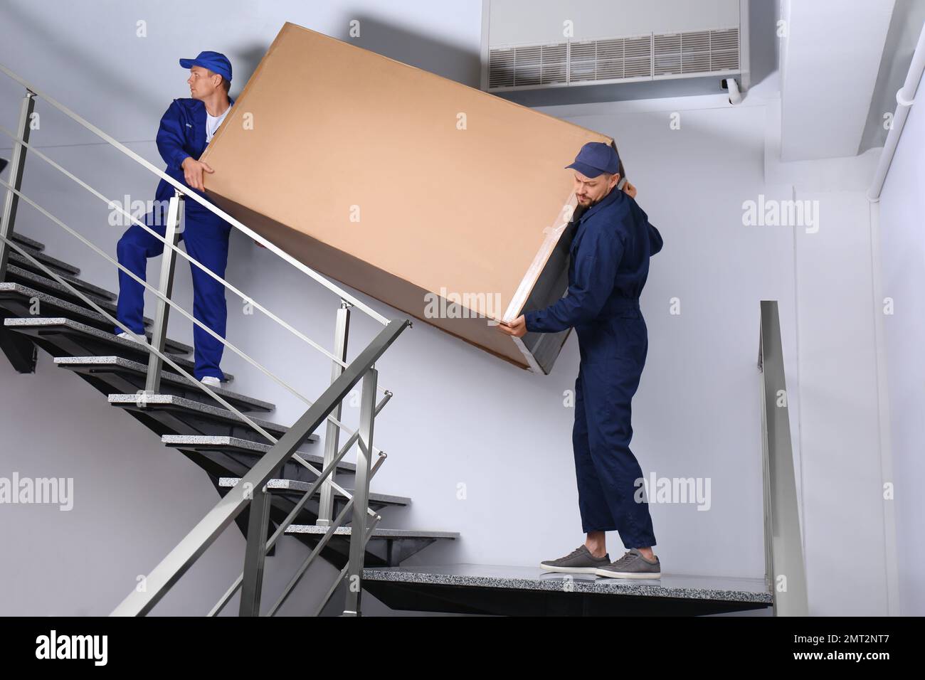 Professional workers carrying refrigerator on stairs indoors Stock ...