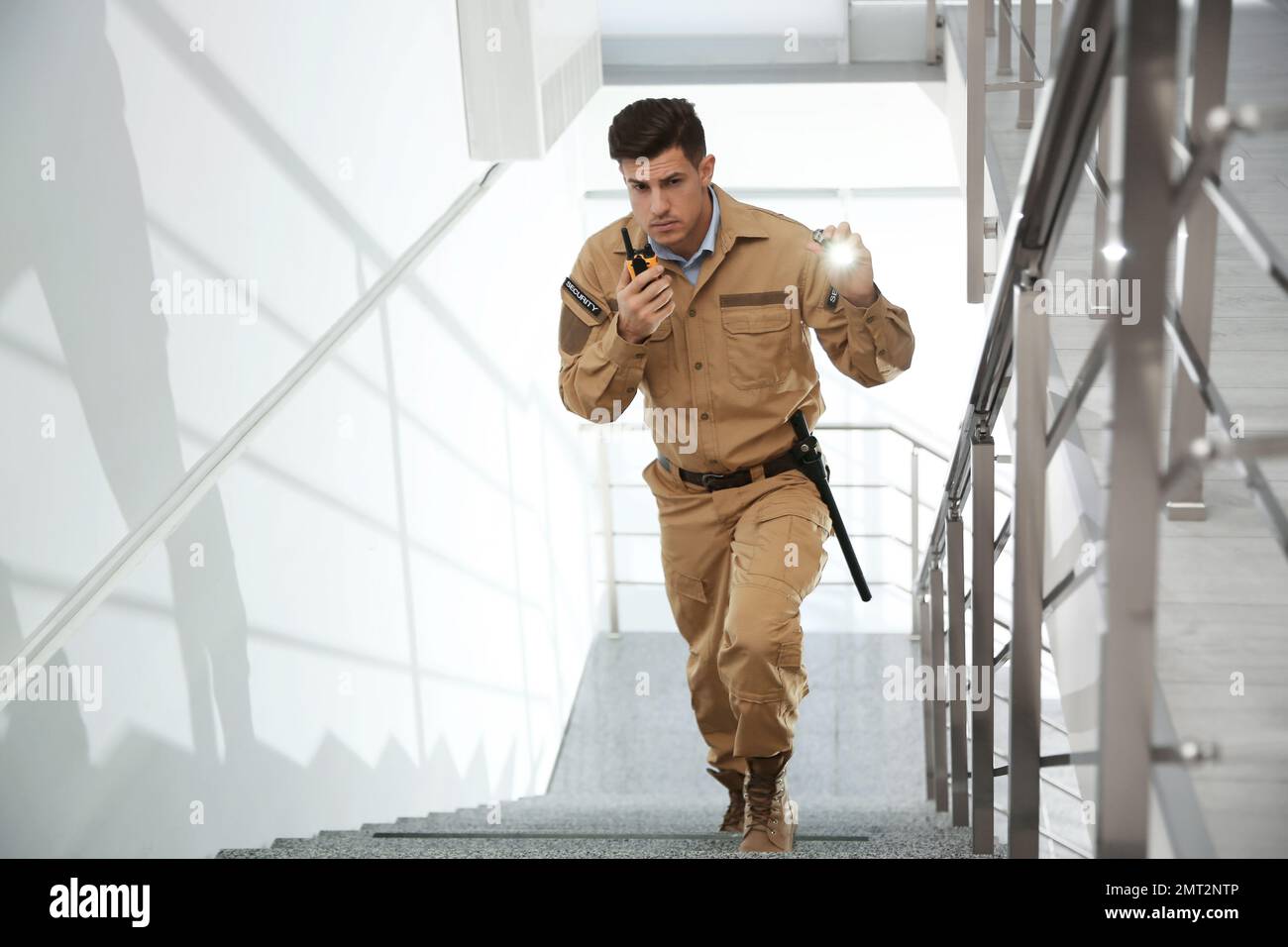 Professional security guard with portable radio set and flashlight on ...