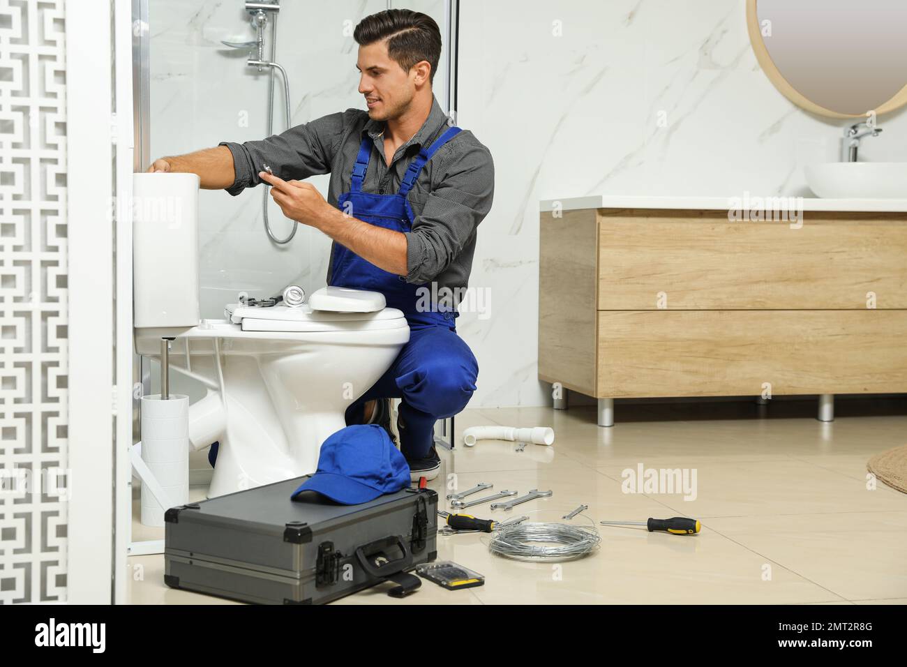 Professional plumber working with toilet bowl in bathroom Stock Photo ...
