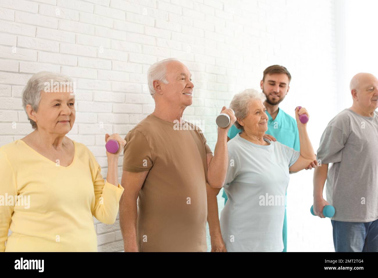 Elderly people training with dumbbells in hospital gym. Senior patients ...