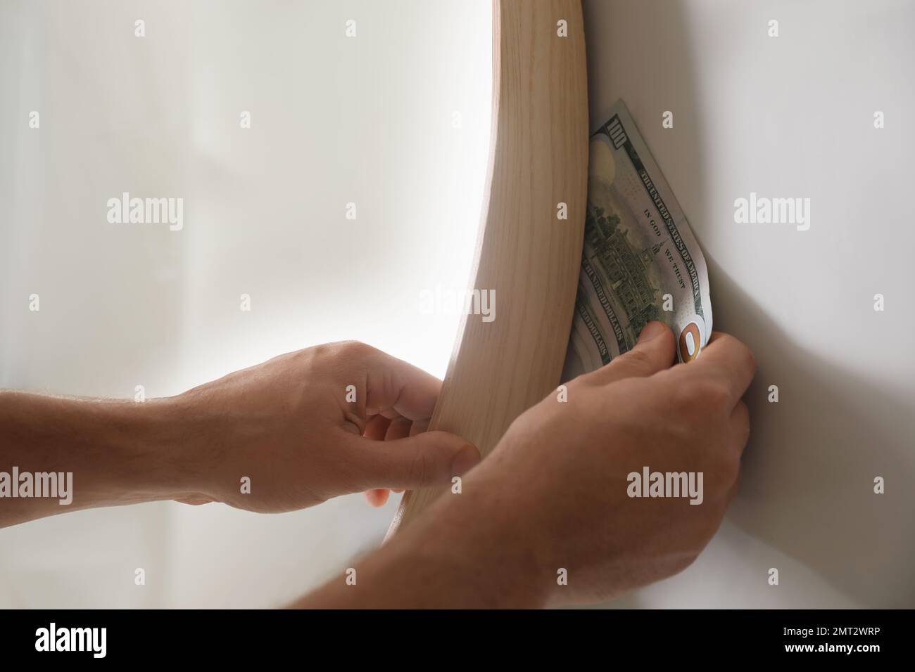 Man hiding money behind mirror indoors, closeup. Financial savings ...