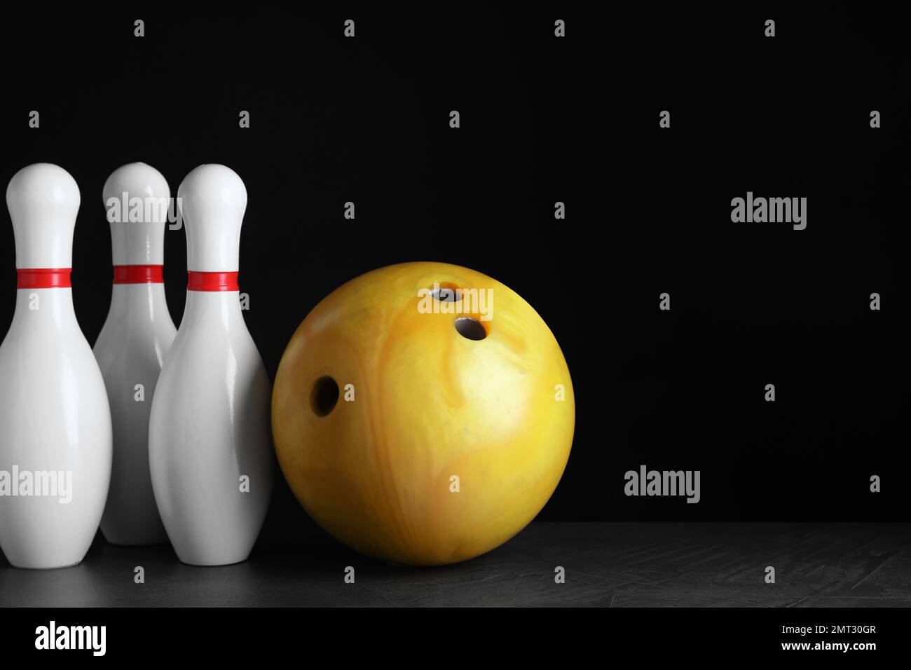 Yellow bowling ball and pins on black stone table Stock Photo - Alamy