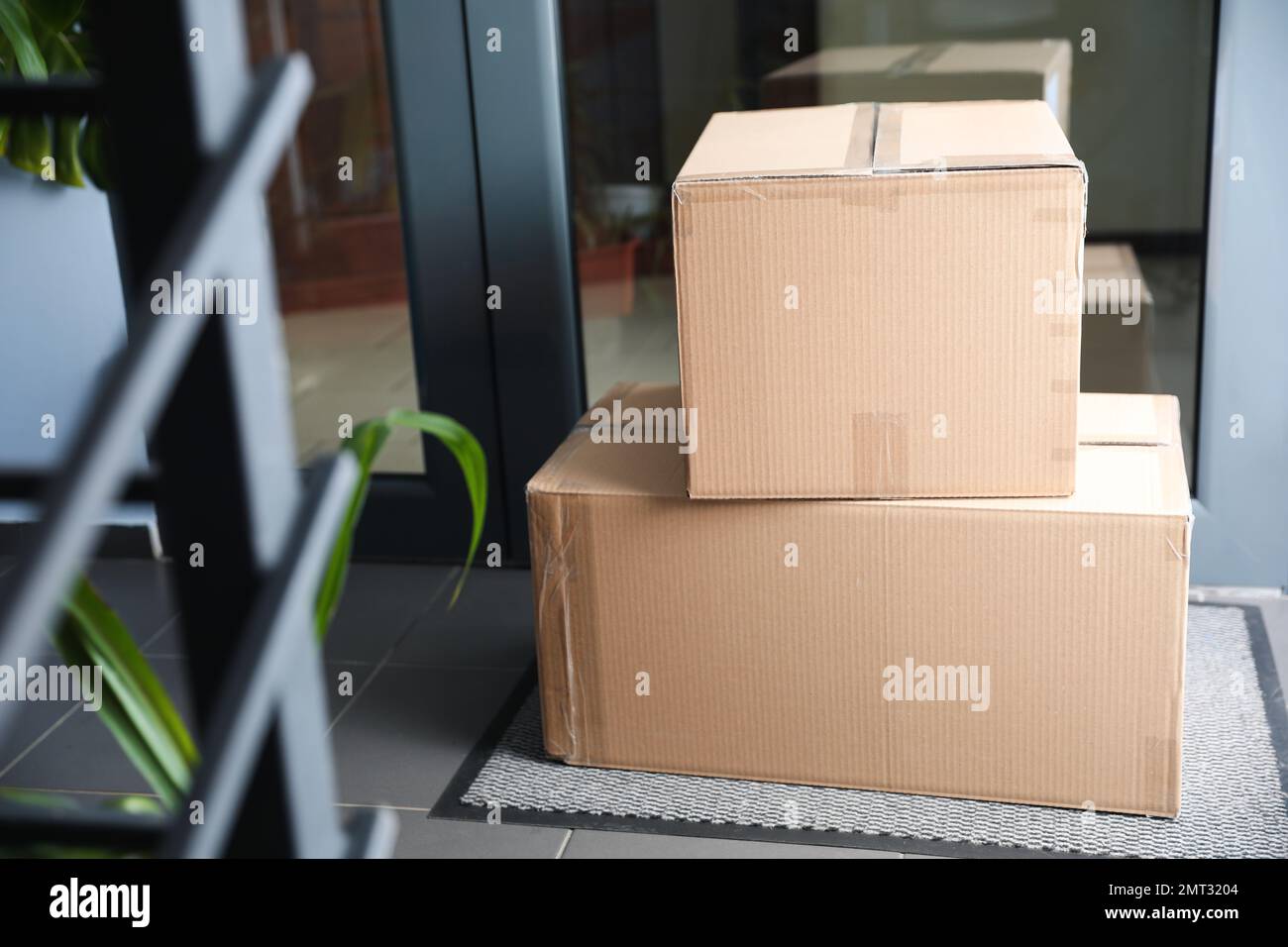 Cardboard boxes on rug near door. Parcel delivery service Stock Photo ...