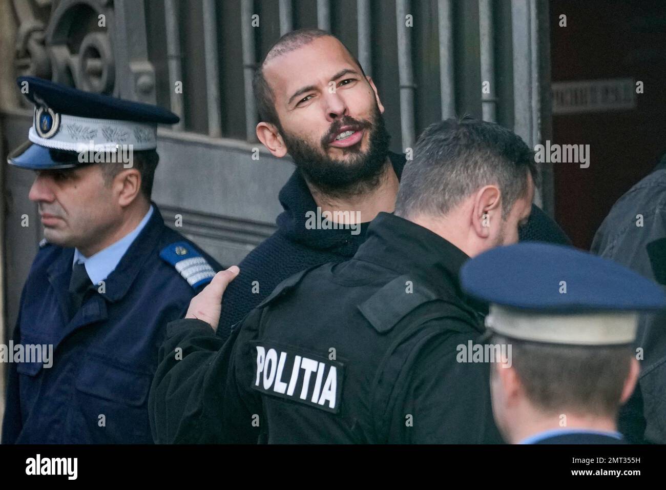 Police officers escort Andrew Tate handcuffed to his brother Tristan ...