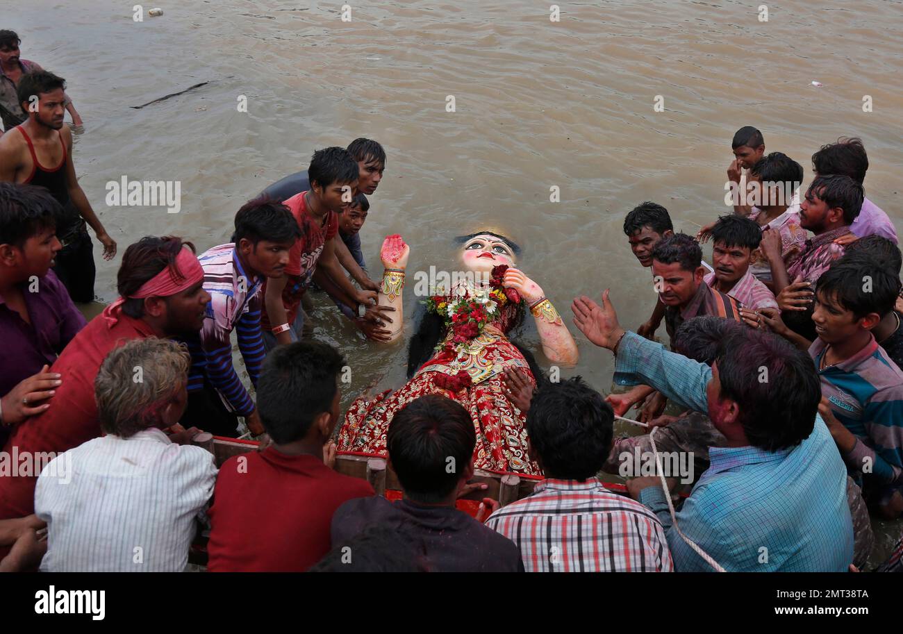Indian devotees immerse an idol of Hindu goddess Dashama in river ...