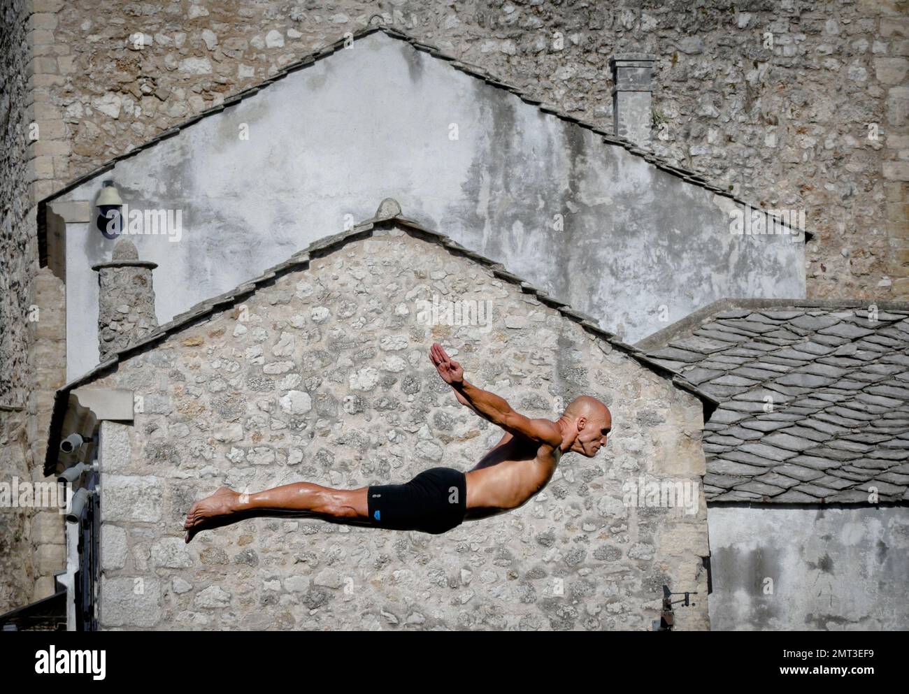 In this photograph taken on Sunday, July 30, 2017, a man dives from the ...