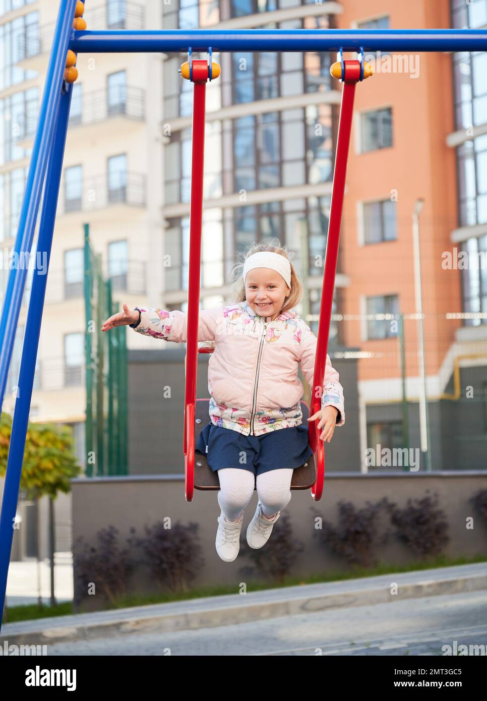 Little female child swaying on swing, having fun at playground ...