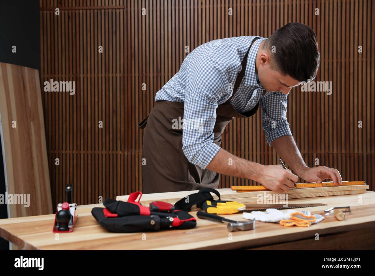 Carpenter marking length of wooden plank with pencil in workshop Stock ...