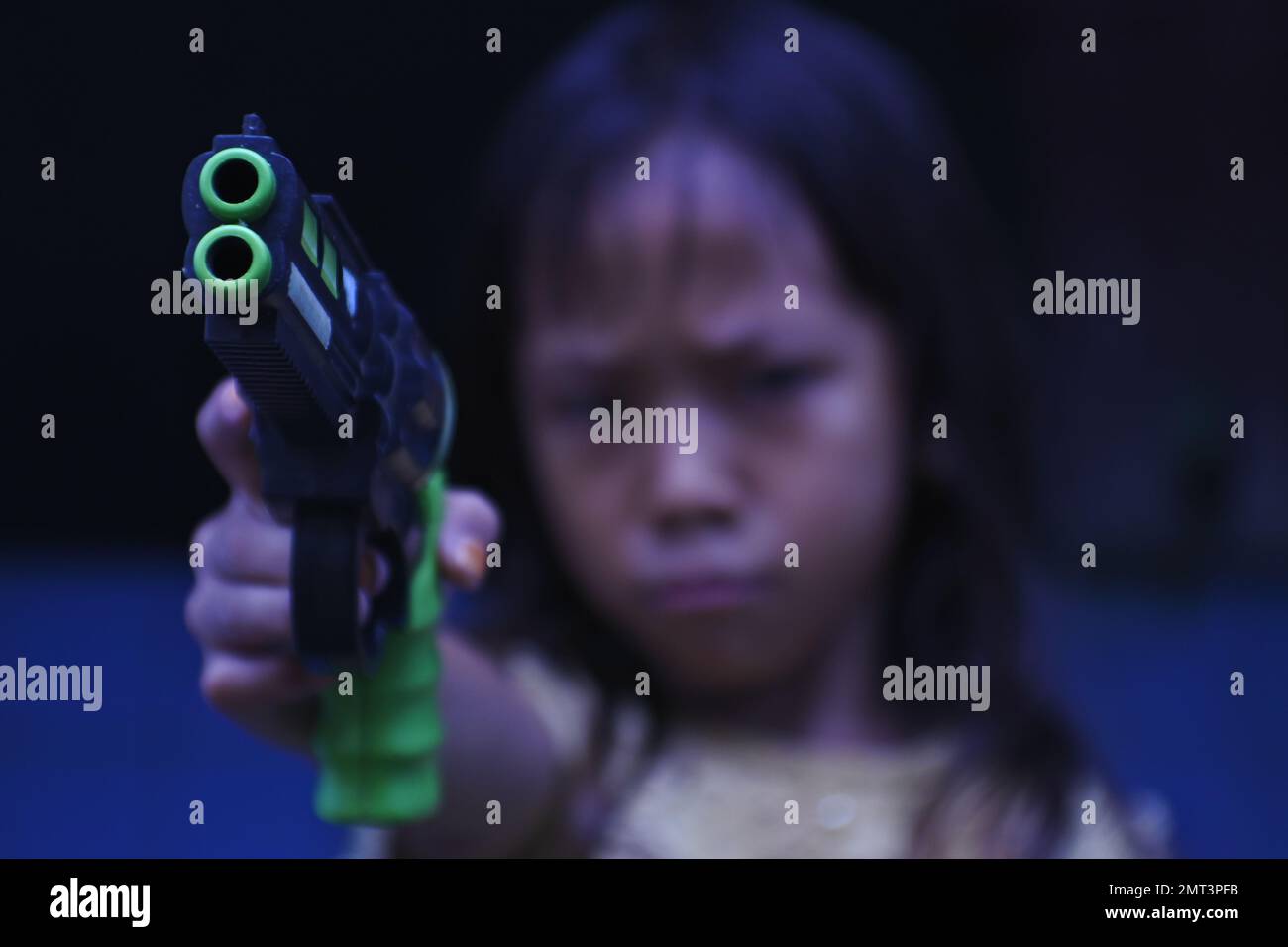 A sad girl pointing a toy gun on the camera in a selective focus Stock ...