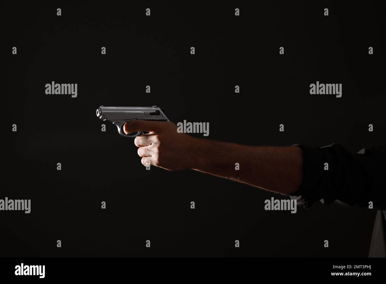 Professional killer with gun on black background, closeup Stock Photo ...