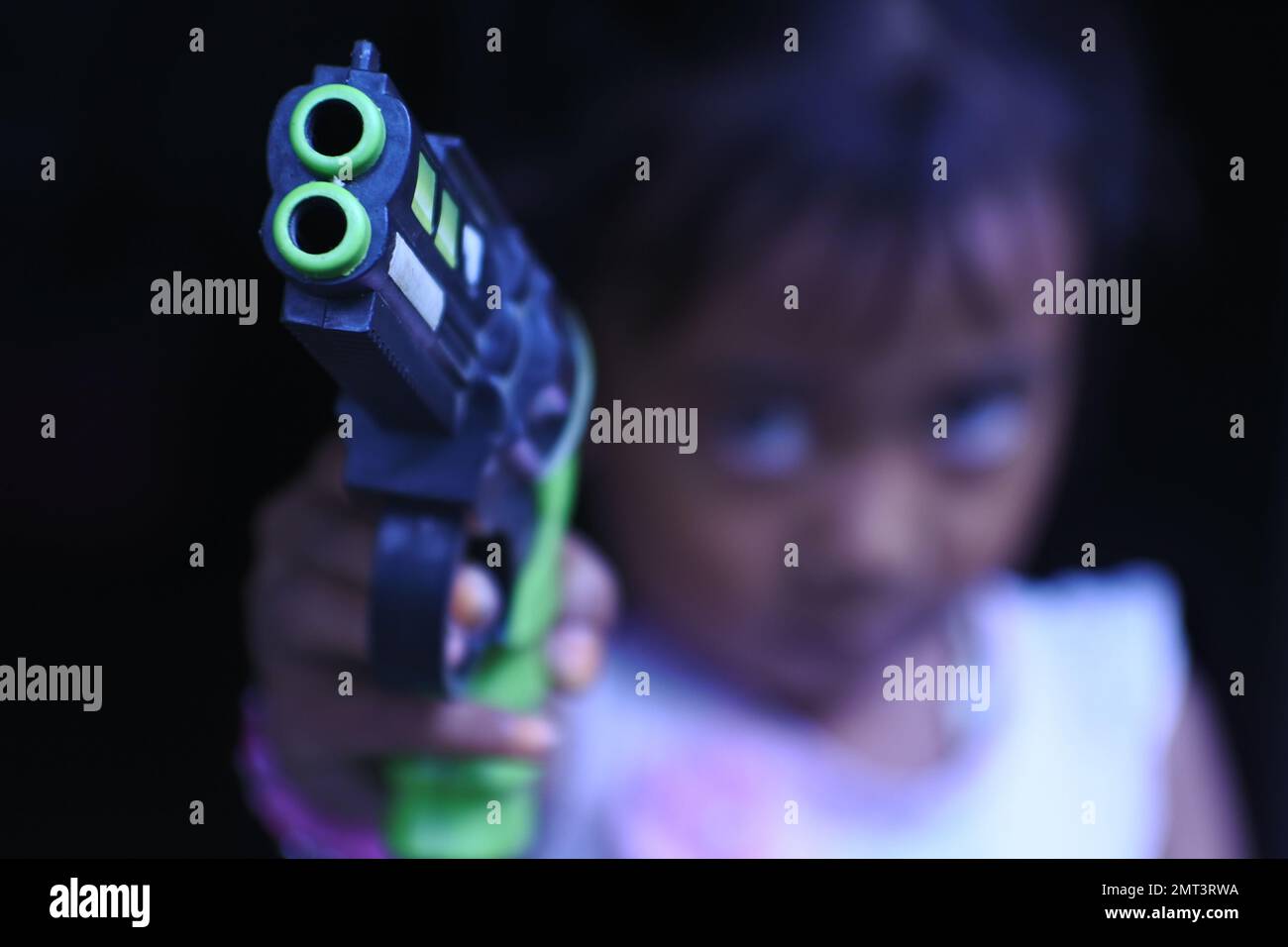 A sad girl pointing a toy gun on the camera in a selective focus Stock ...