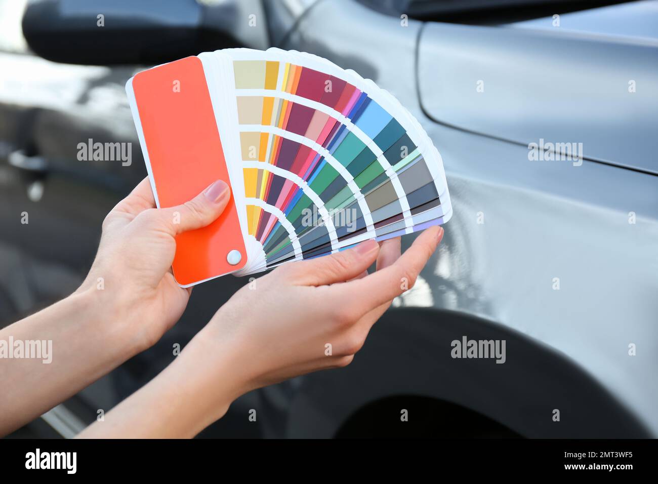 Woman with palette samples choosing color for painting car, closeup ...