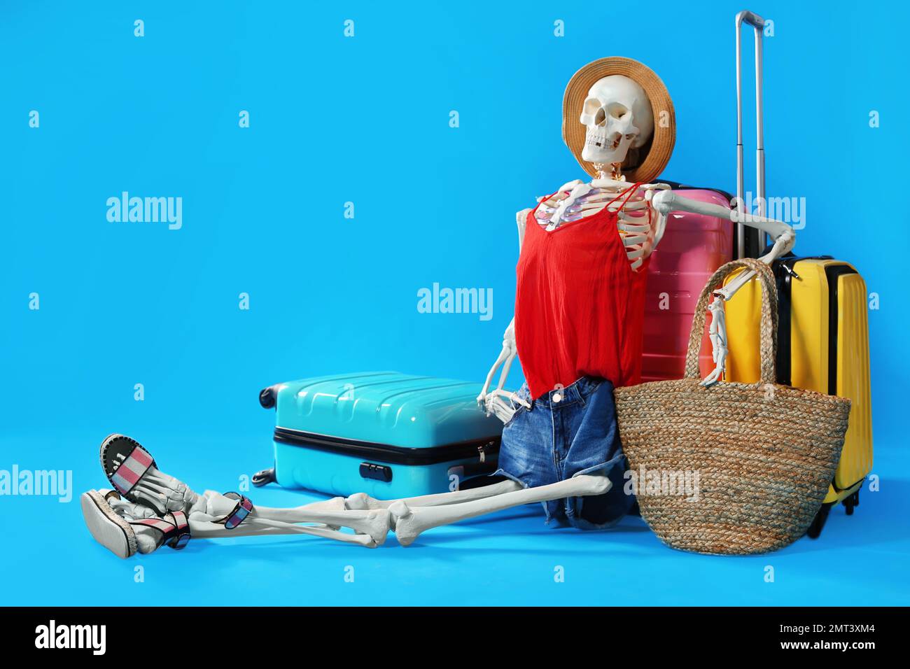 Human skeleton in summer clothes with suitcases on blue background ...