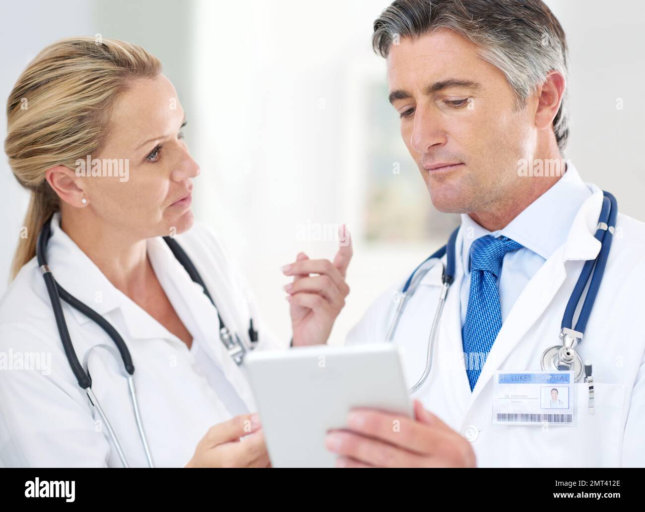 Comparing medical notes. two doctors talking together over a digital ...