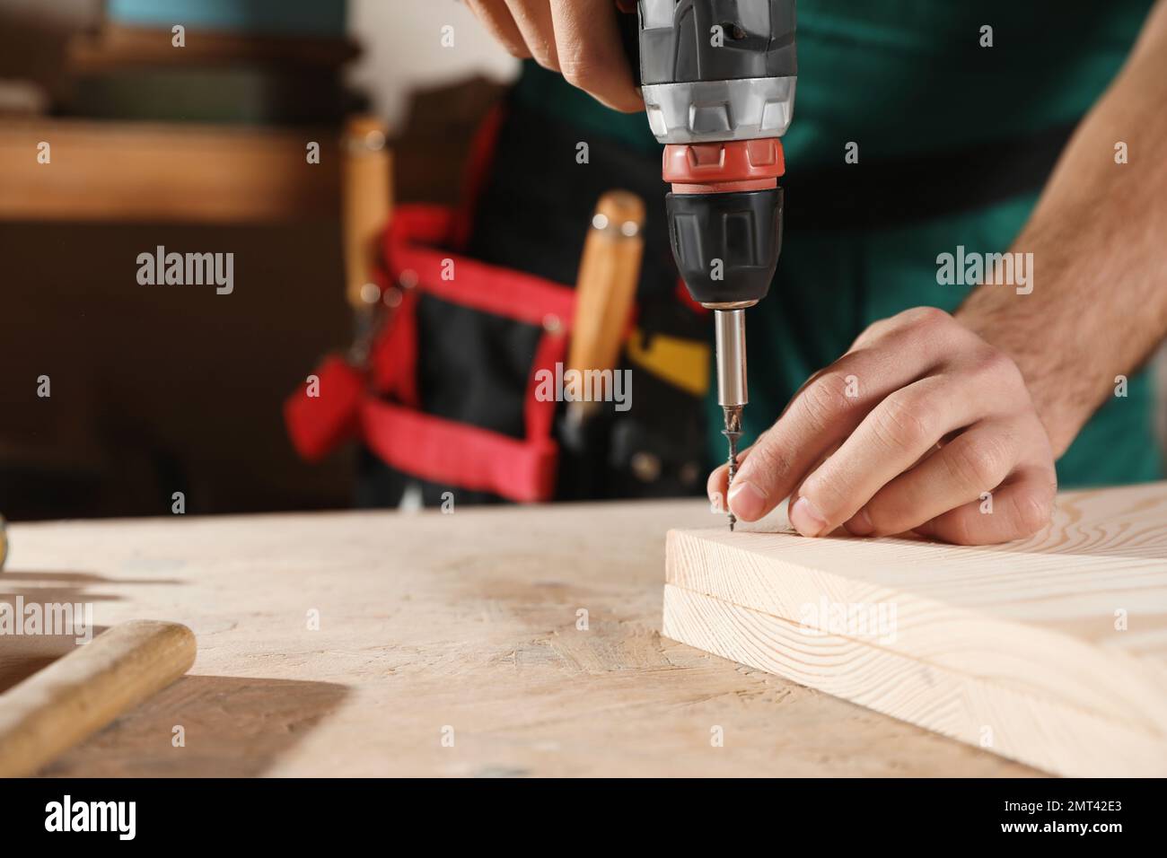 Professional carpenter twisting screw with drill at workbench, closeup ...