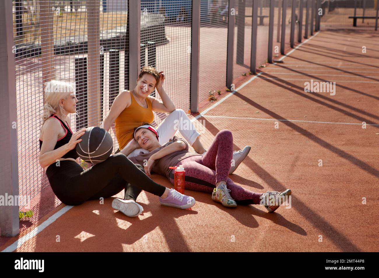 Happy mature women relax on court after playing basketball. Female ...