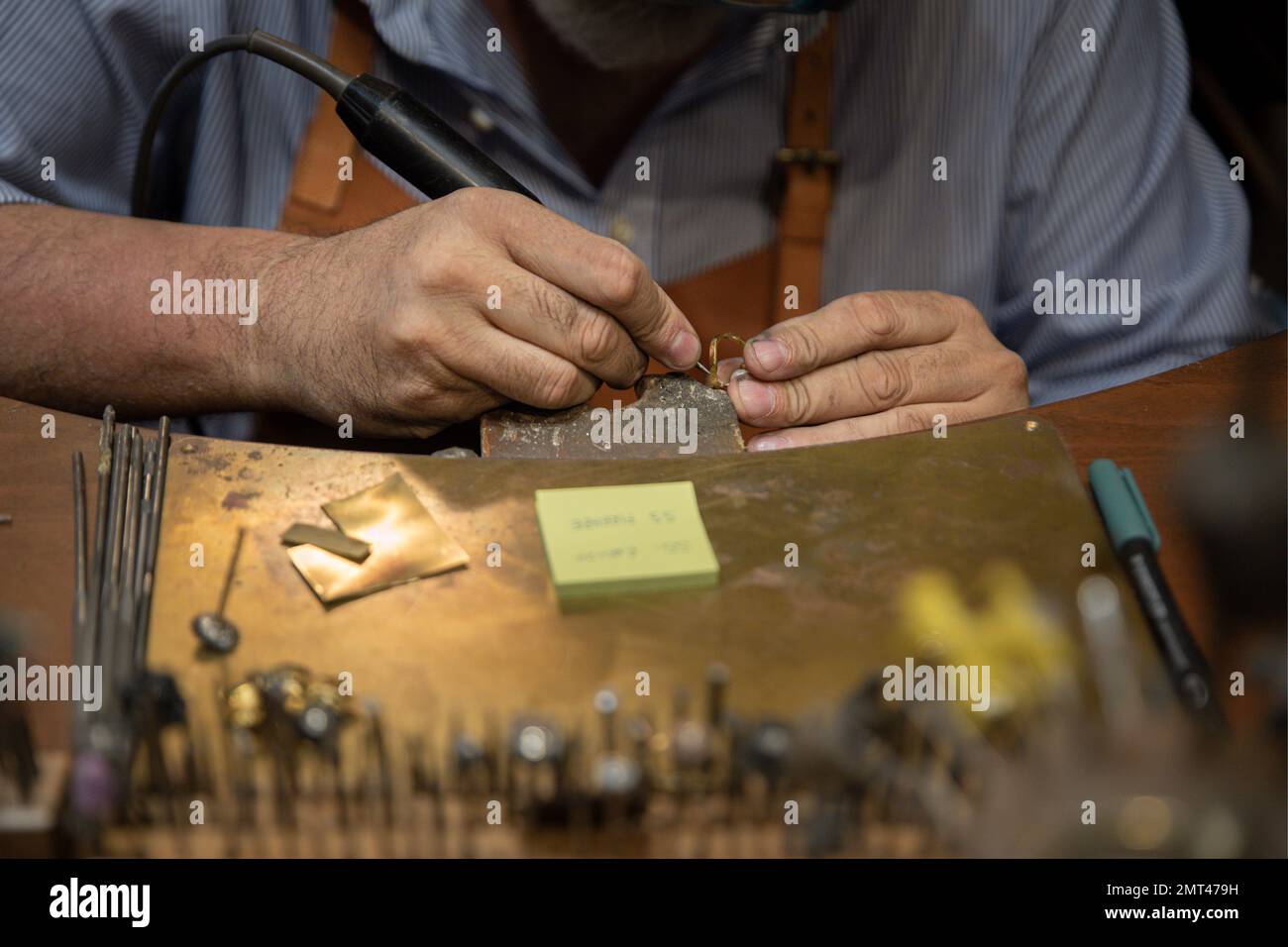 Silversmith working with tools on a jewelers bench in a traditional ...