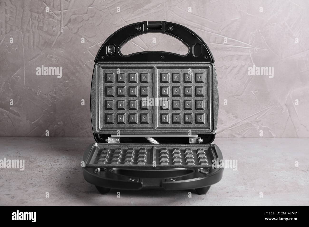 Modern waffle iron on grey stone table Stock Photo - Alamy