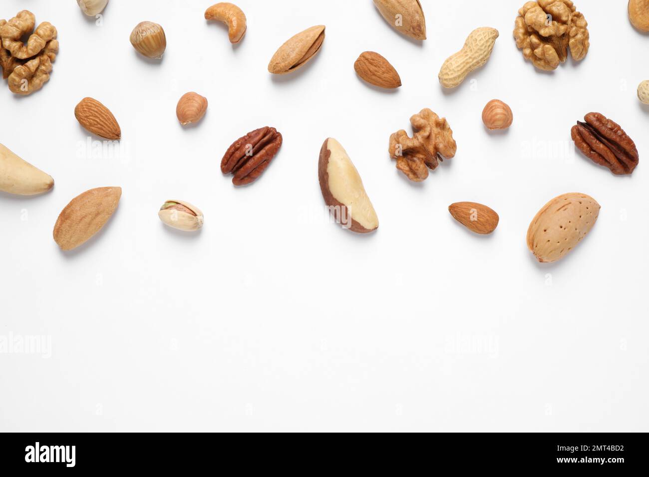 Different delicious nuts on white background, flat lay. Space for text ...