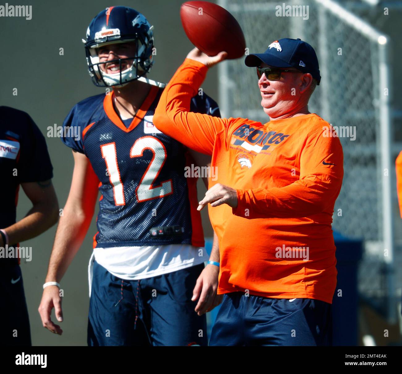 Denver Broncos quarterback coach Bill Musgrave, front, tosses a pass as ...