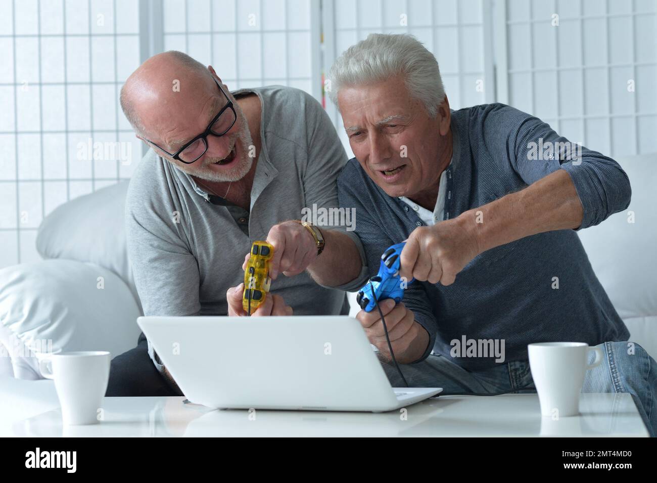 Two old men sitting at table and playing video game Stock Photo - Alamy