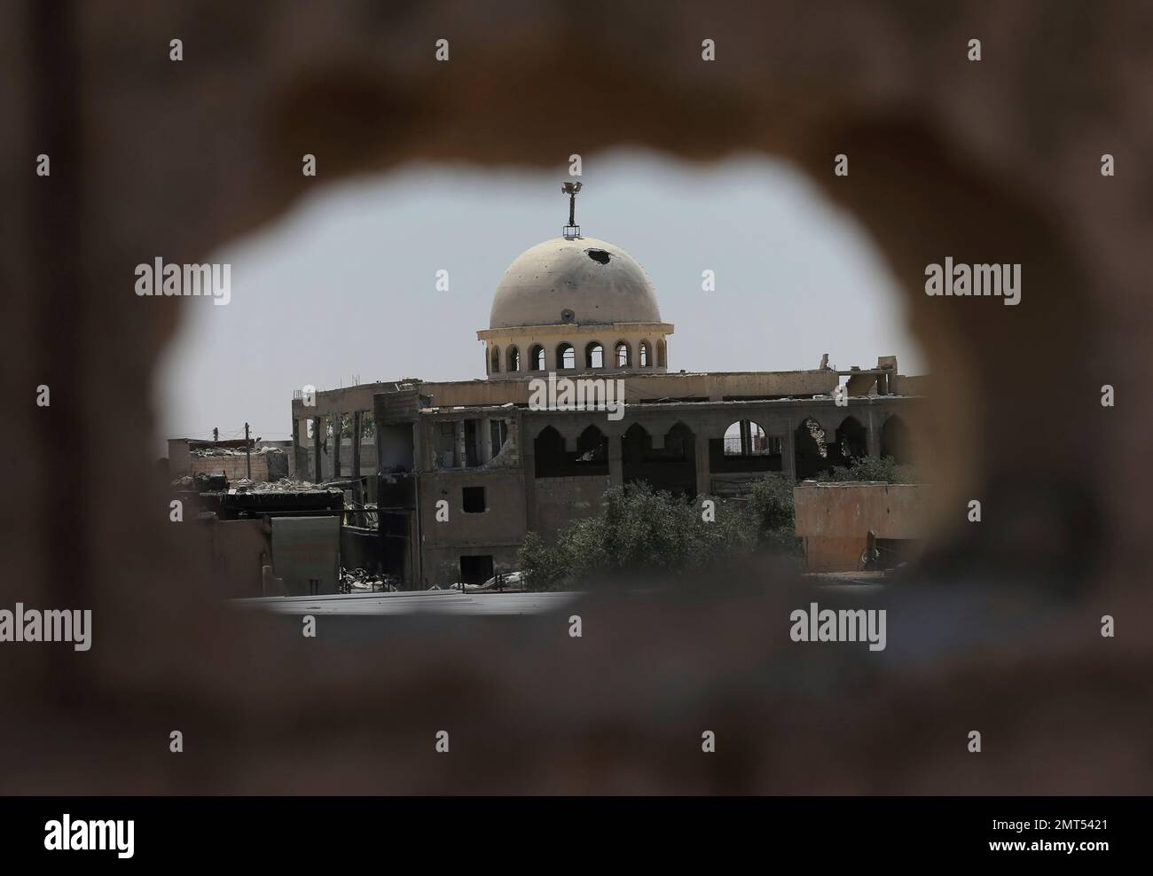 A destroyed mosque is seen through a hole of U.S.-backed Syrian ...