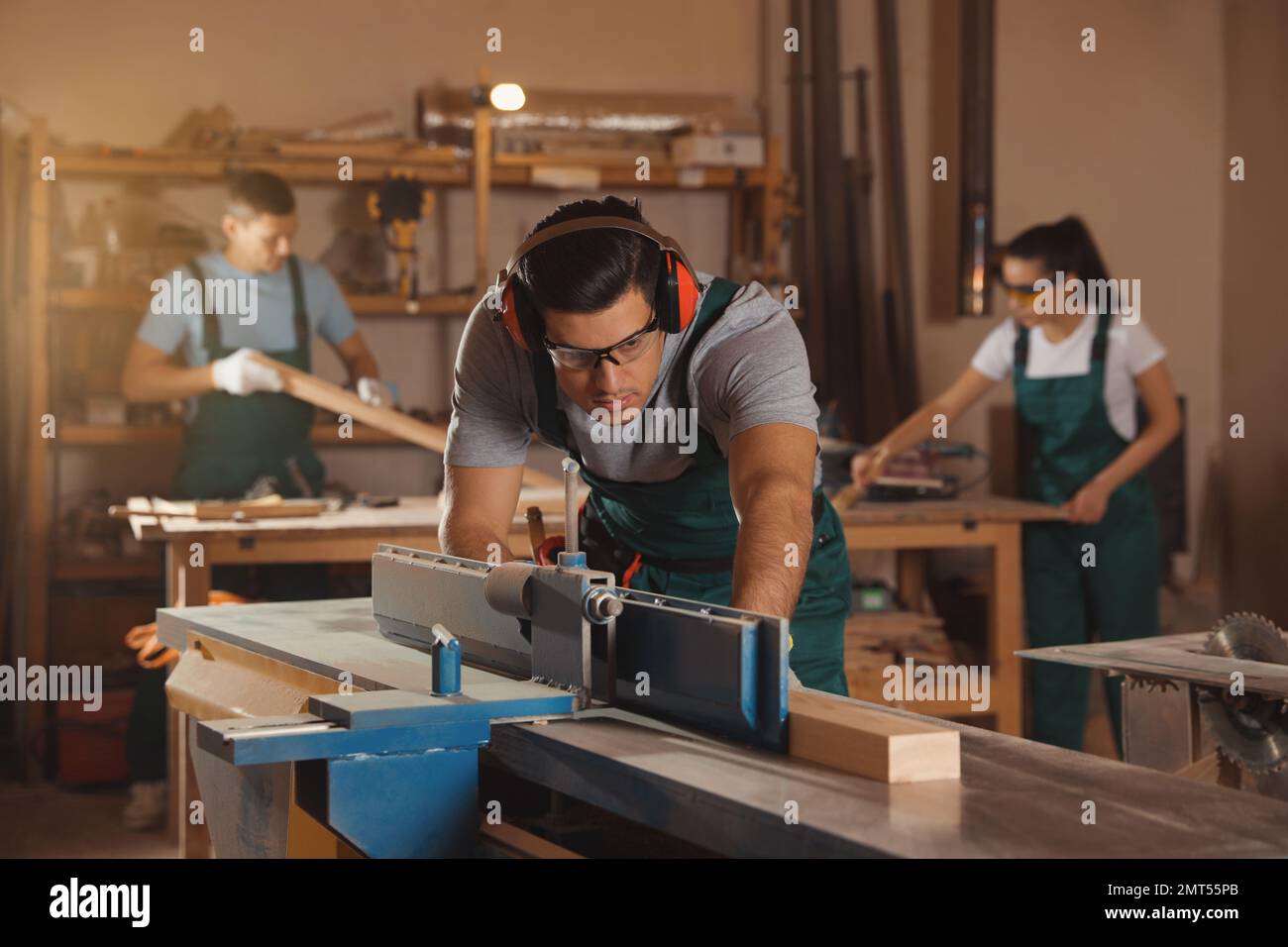 Professional carpenter working with surface planer and colleagues in workshop Stock Photo - Alamy