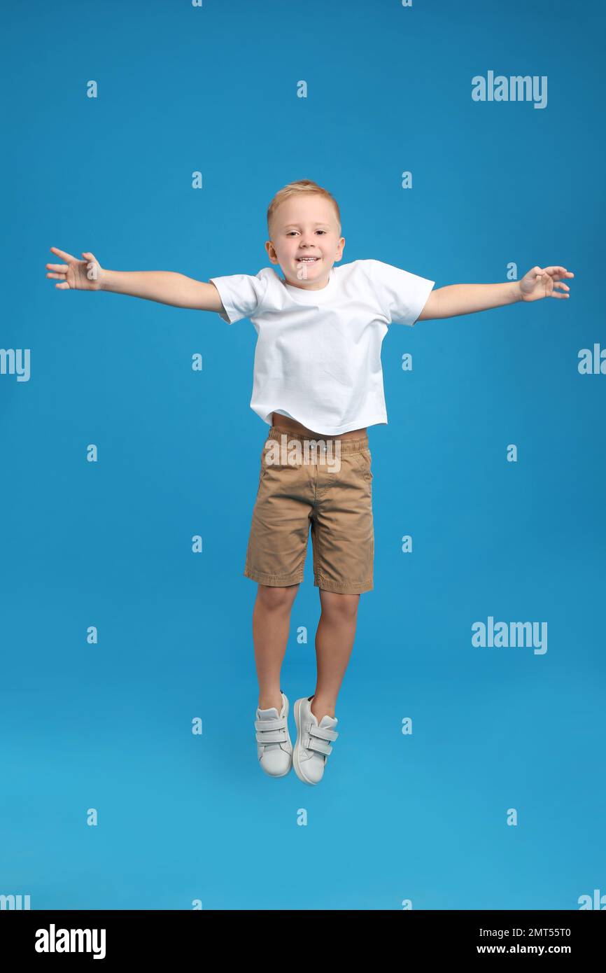 Cute little boy jumping on light blue background Stock Photo - Alamy
