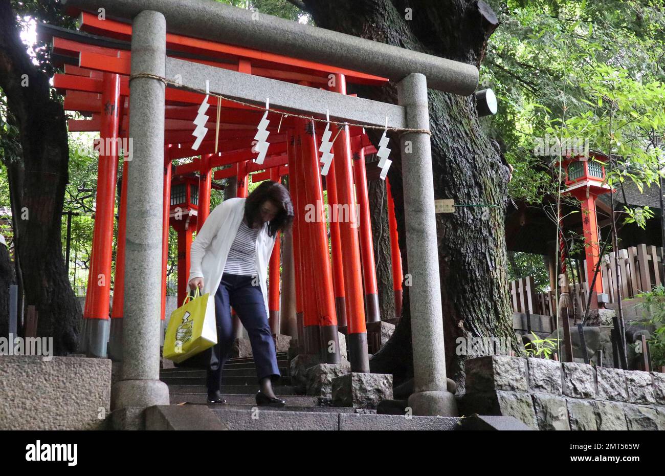 A woman walks through a "torii," a traditional Japanese gate, at Nogi Shrine in Tokyo, Wednesday ...