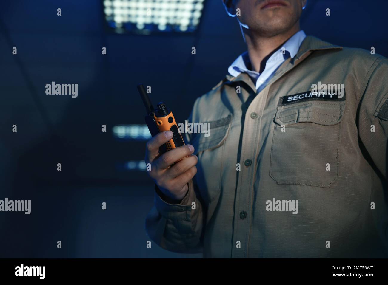 Professional security guard with portable radio set in dark room ...