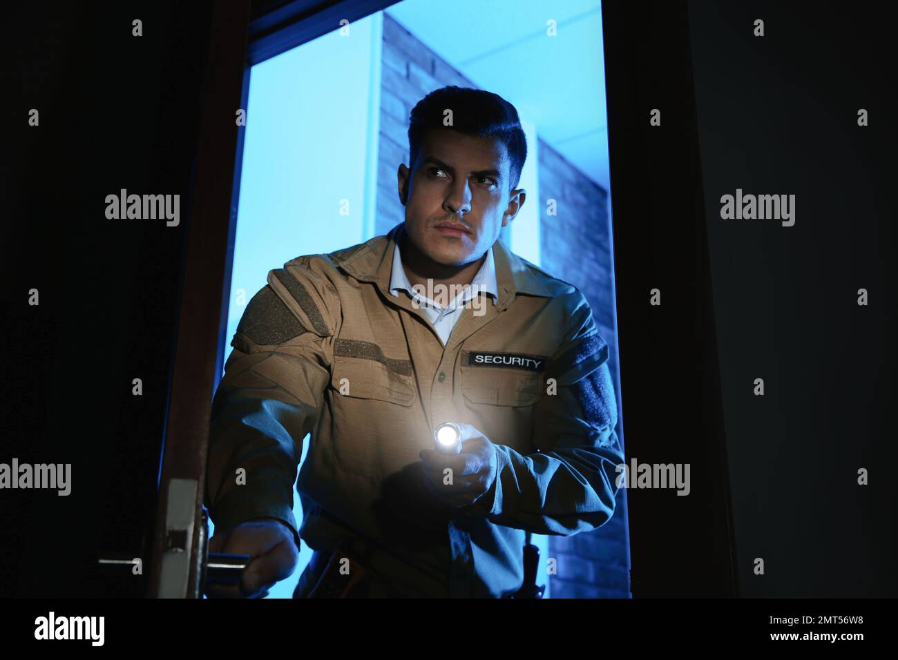 Professional security guard with flashlight checking dark room Stock ...