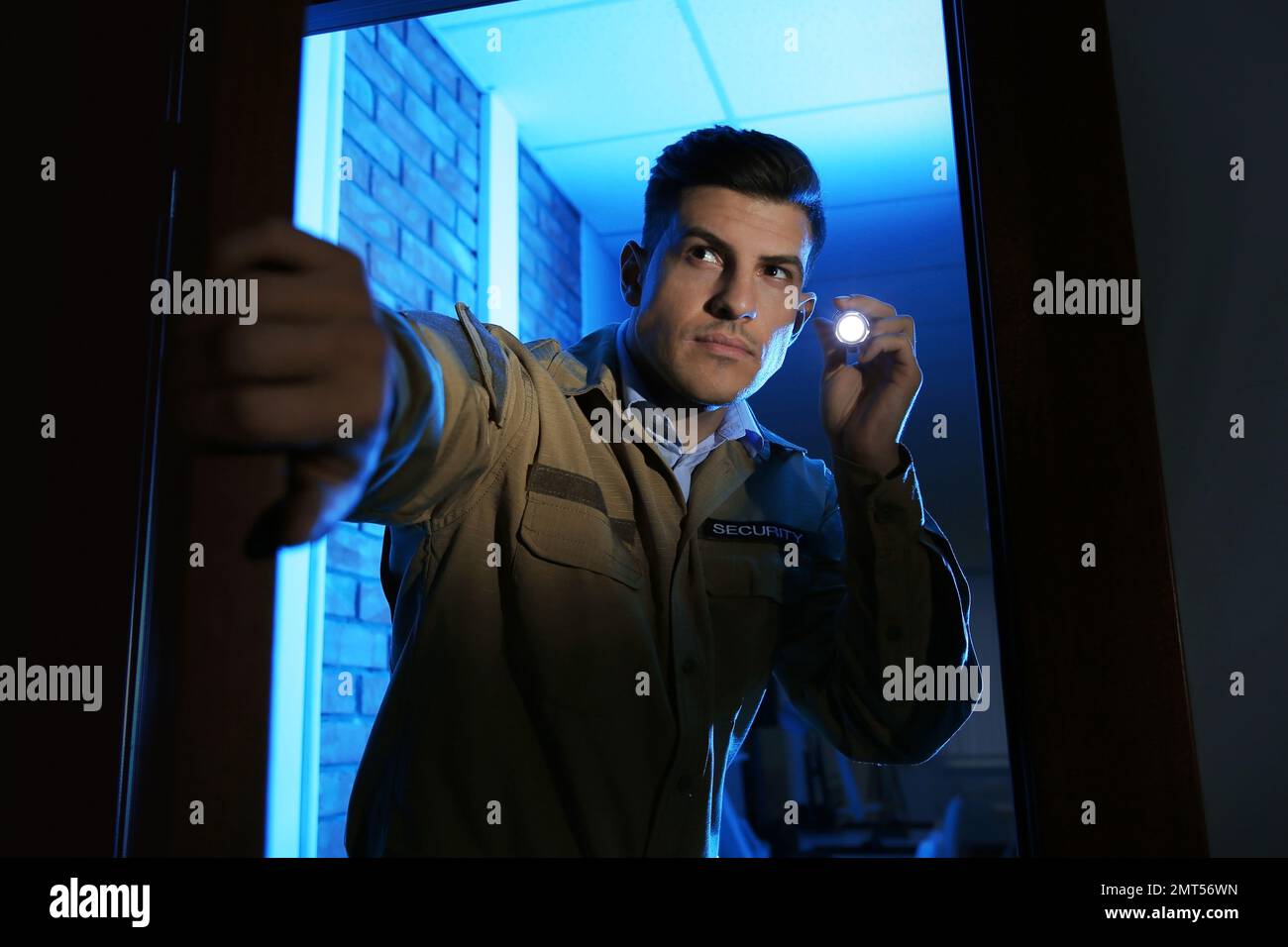 Professional security guard with flashlight checking dark room Stock ...