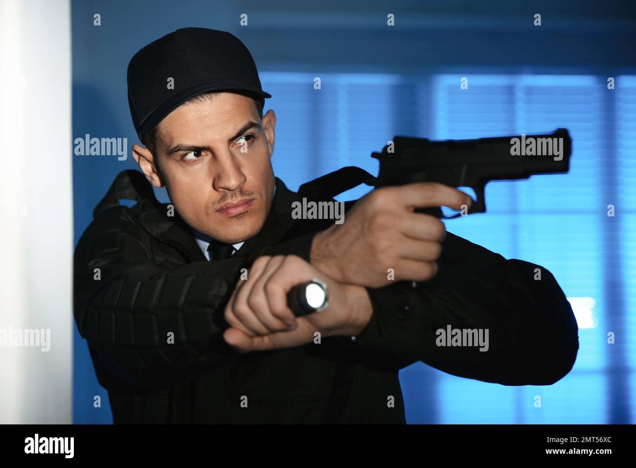 Professional security guard with flashlight and gun in dark room Stock ...