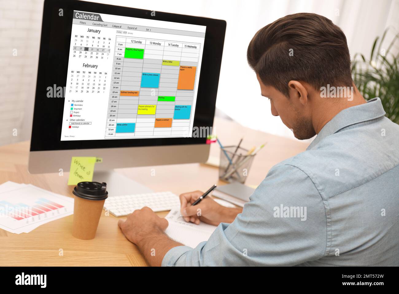 Man planning his schedule with calendar app on computer in office Stock ...