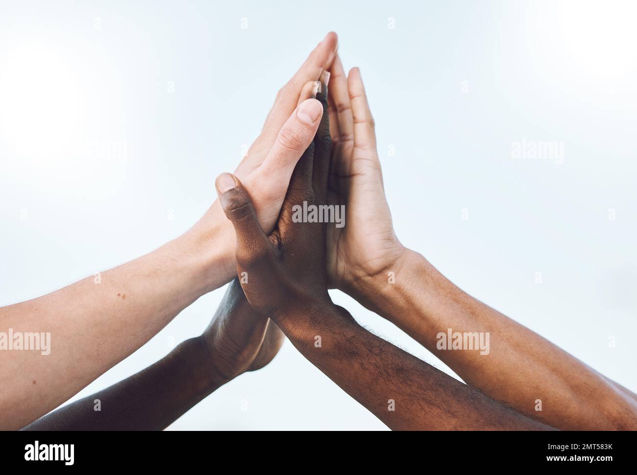 Sports, teamwork and hands high five for support, motivation and community with blue sky ...