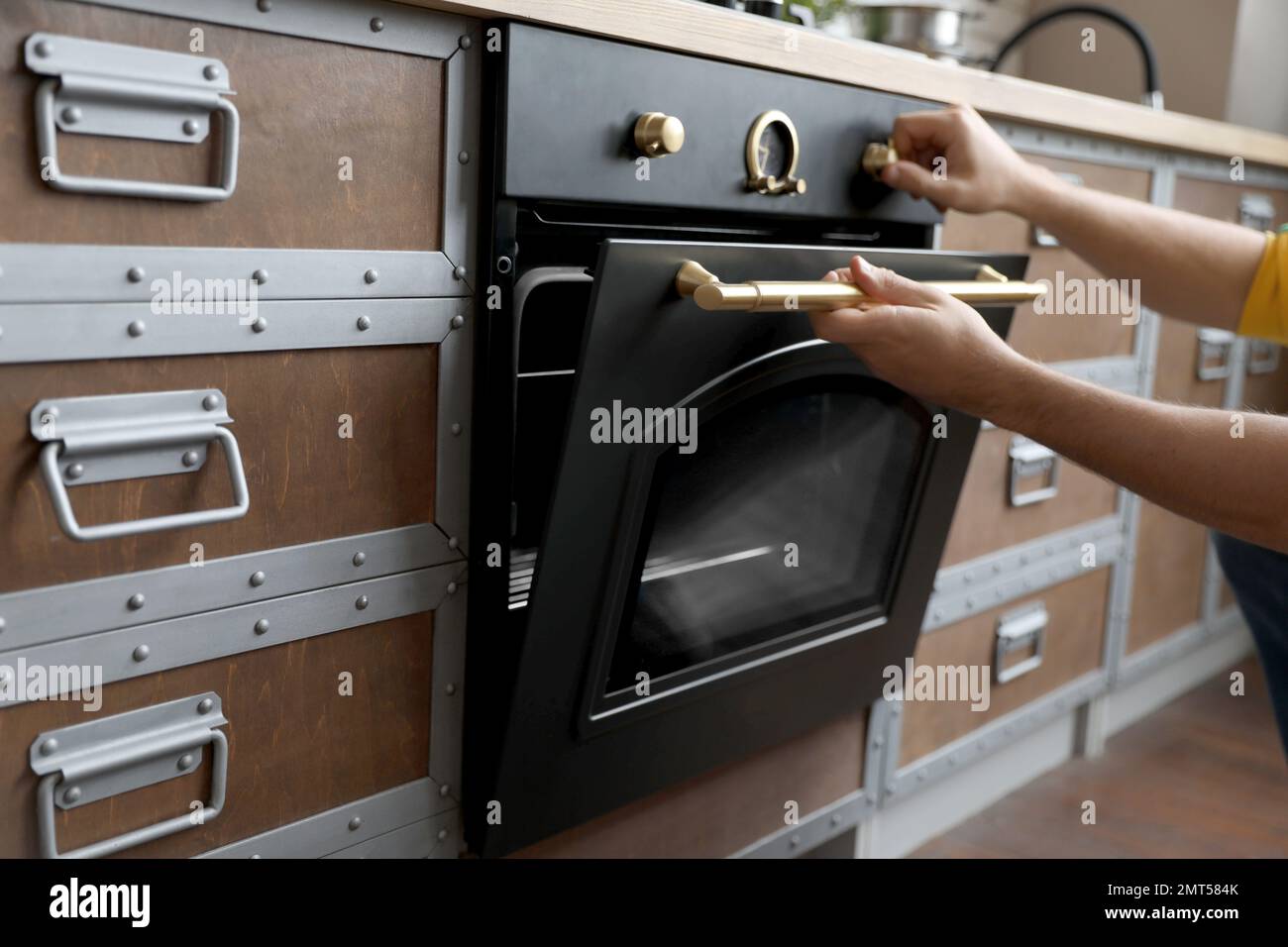 Man using modern oven in kitchen, closeup Stock Photo - Alamy