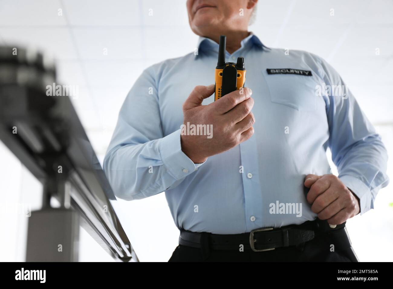 Professional security guard with portable radio set indoors, closeup ...
