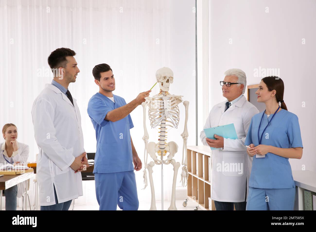 Medical students and professor studying human skeleton anatomy in ...