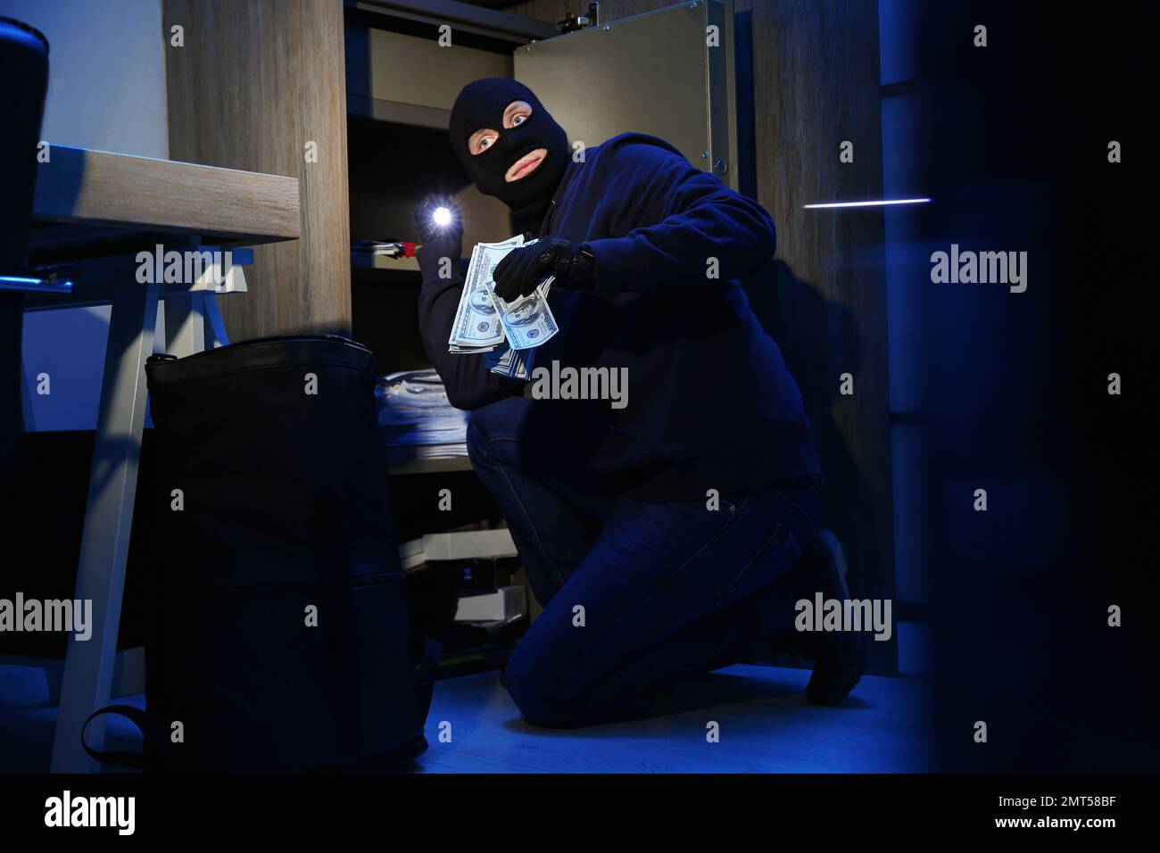 Thief taking money out of steel safe indoors at night Stock Photo - Alamy