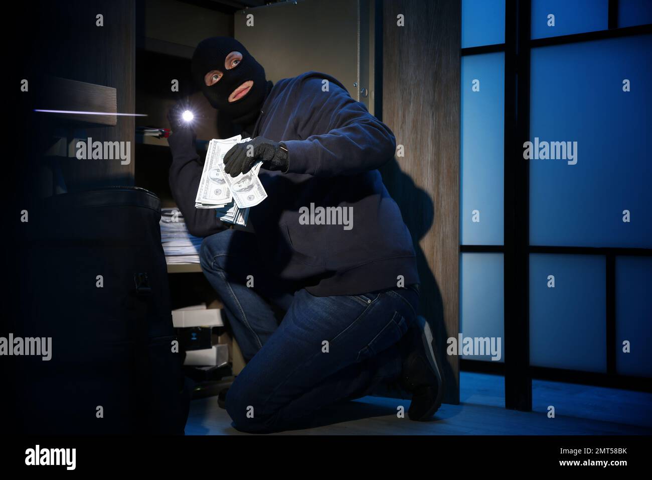 Thief taking money out of steel safe indoors at night Stock Photo - Alamy