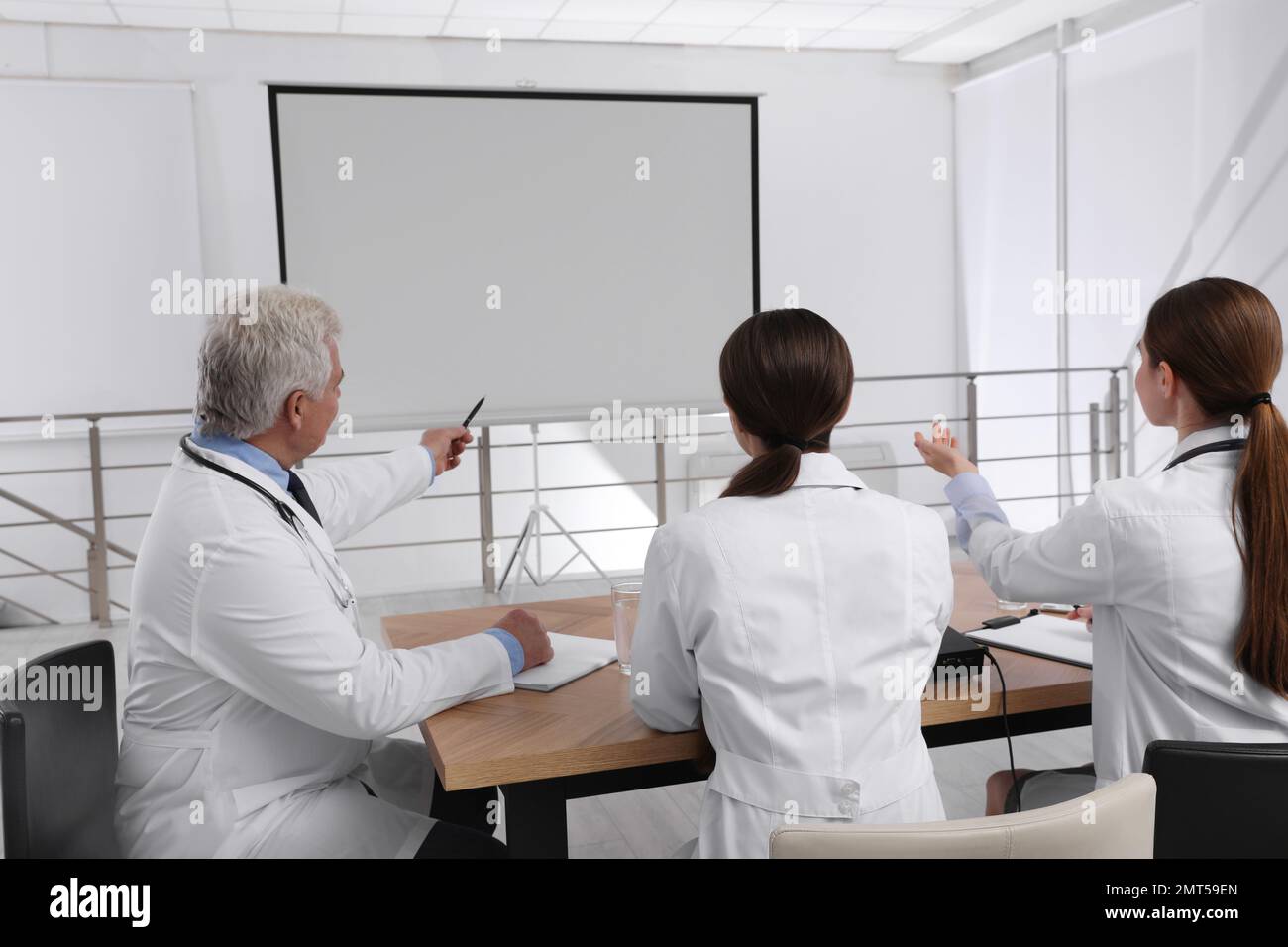 Team of doctors using video projector during conference indoors Stock ...