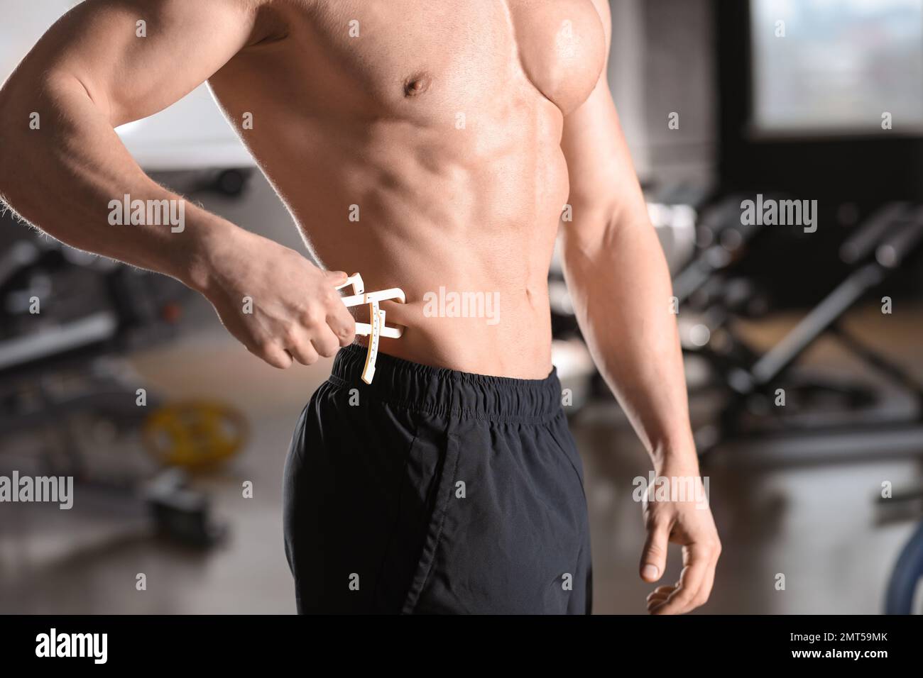 Man measuring body fat layer with caliper indoors, closeup Stock Photo ...